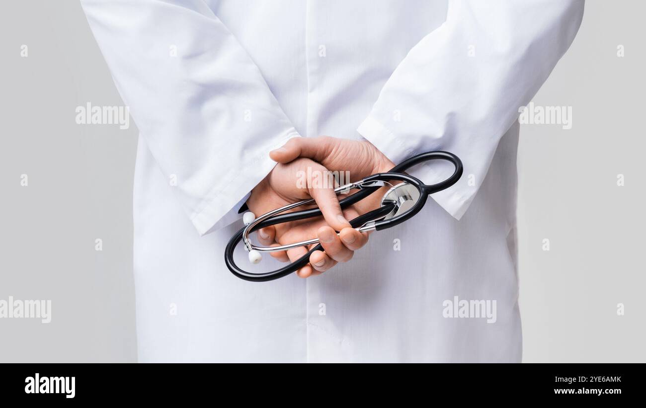 Medical Equipment. Male doctor holding stethoscope behind his back ...