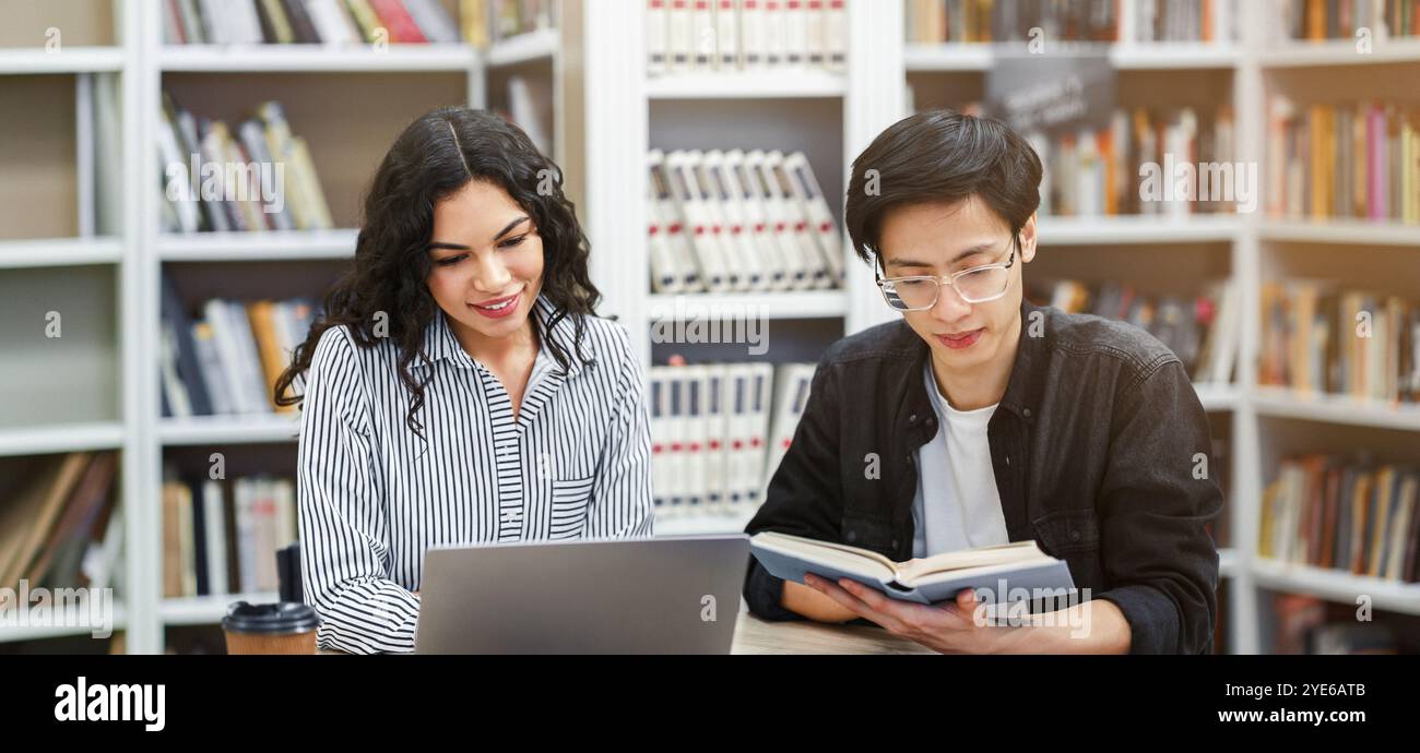Two smiling multicultural students learning at public library Stock ...