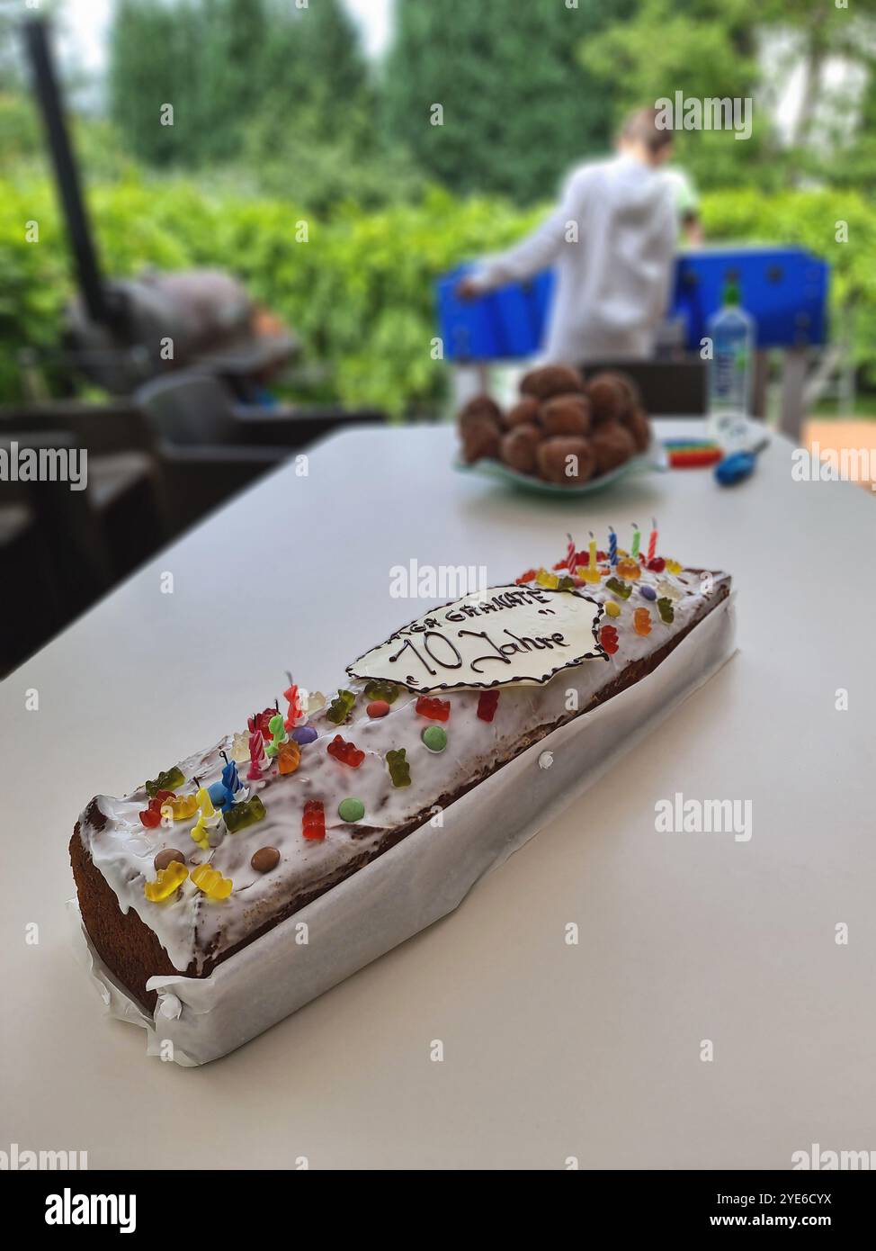 solid birthday cake decorated with gummy bears on a table in the garden ...