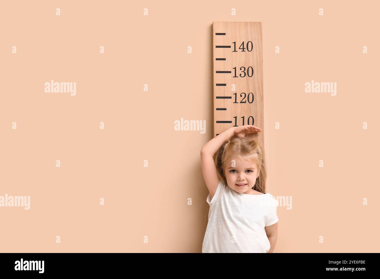 Cute little girl measuring height on beige background Stock Photo - Alamy