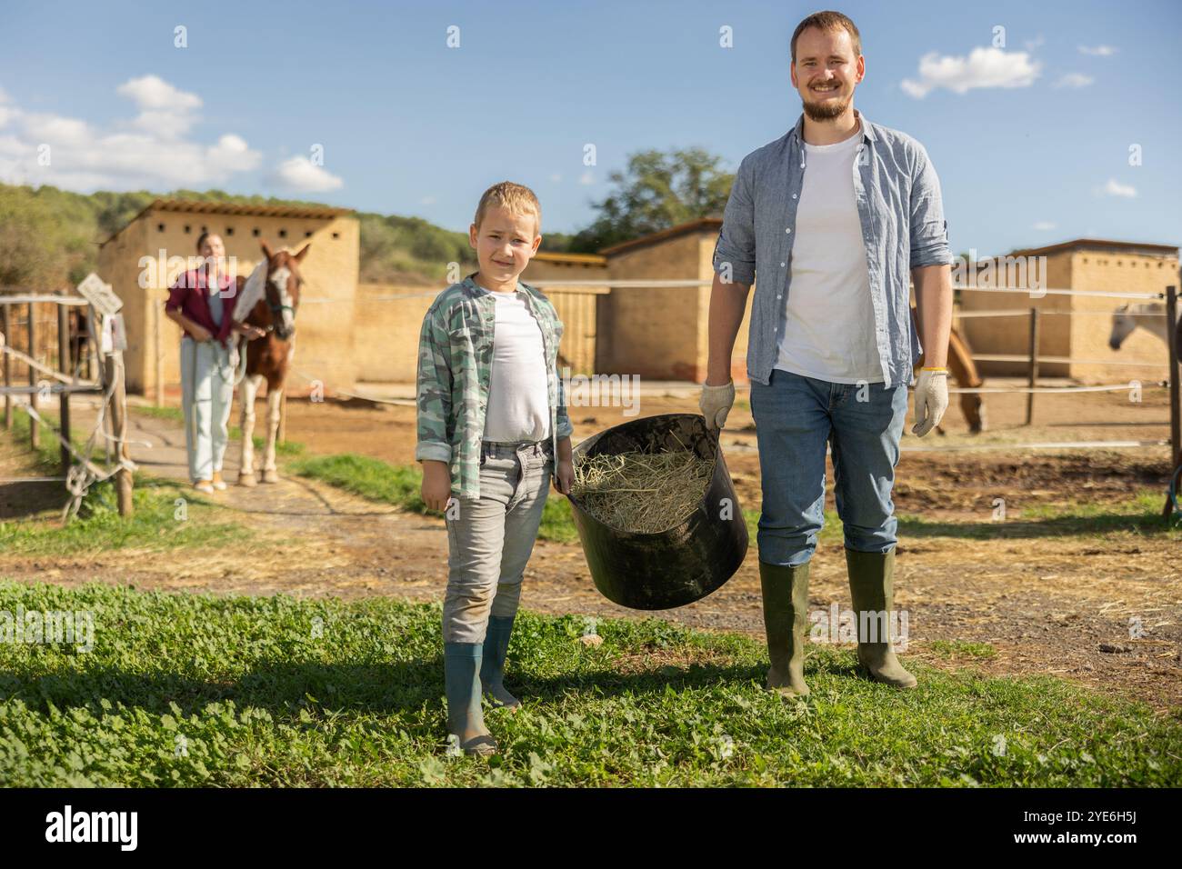 Man and boy with bucket of hay feed for horse Stock Photo - Alamy