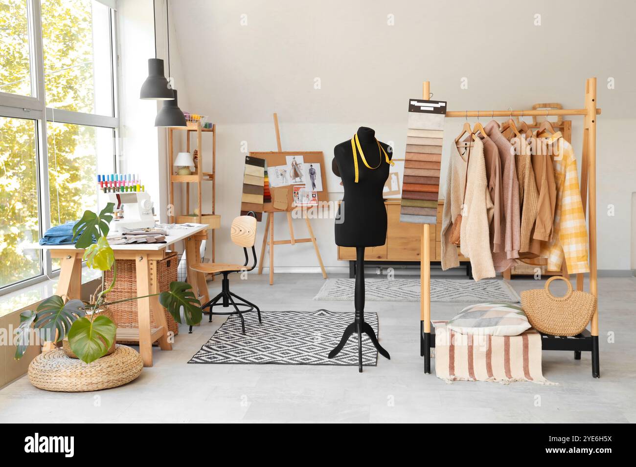 Interior of fashion designer's studio with workplace, clothes rack and ...