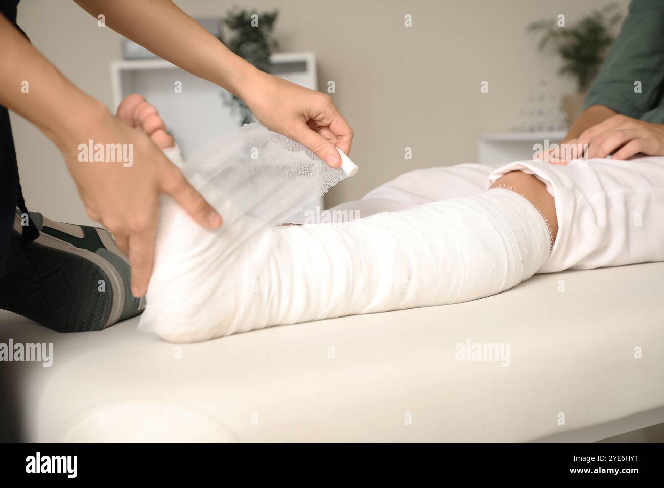 Female doctor bandaging woman's broken leg in clinic, closeup Stock ...