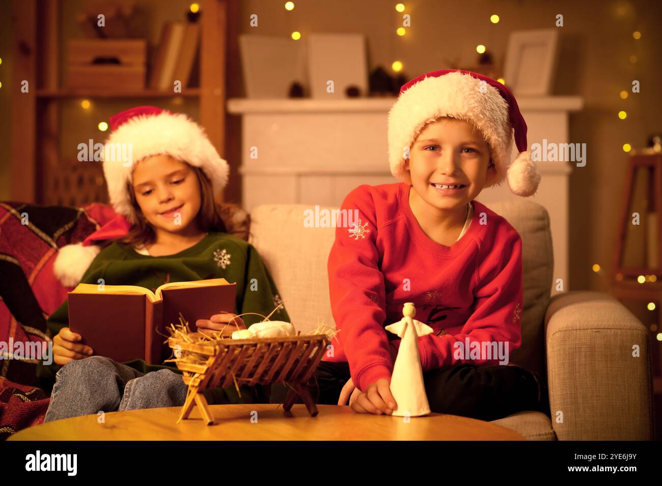 Little children with manger and angel reading Christmas story at home ...