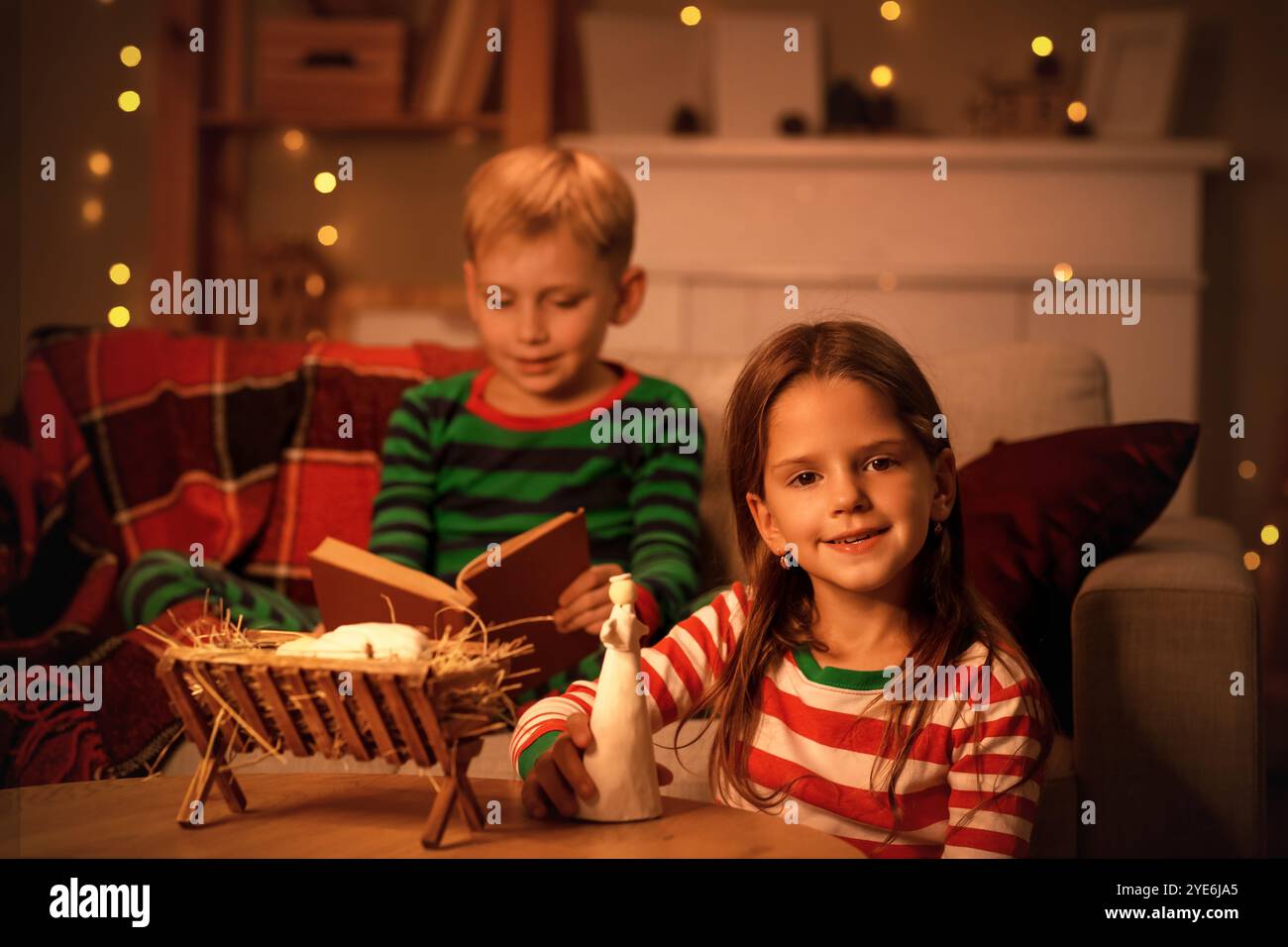 Little girl with angel and her brother reading Christmas story at home ...