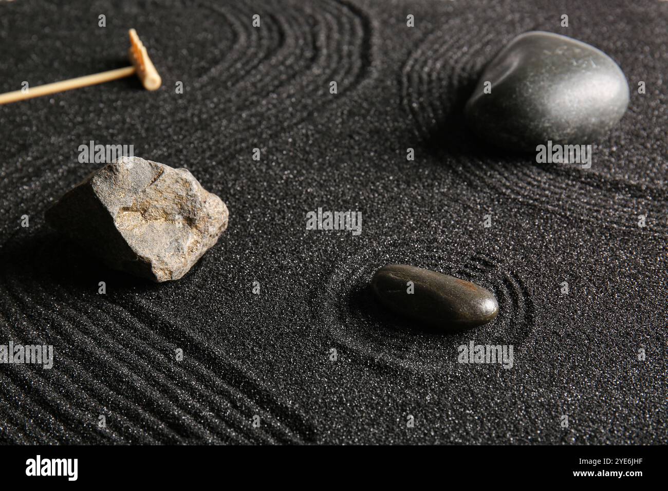Stones with small rake on black sand with lines in Japanese rock garden ...