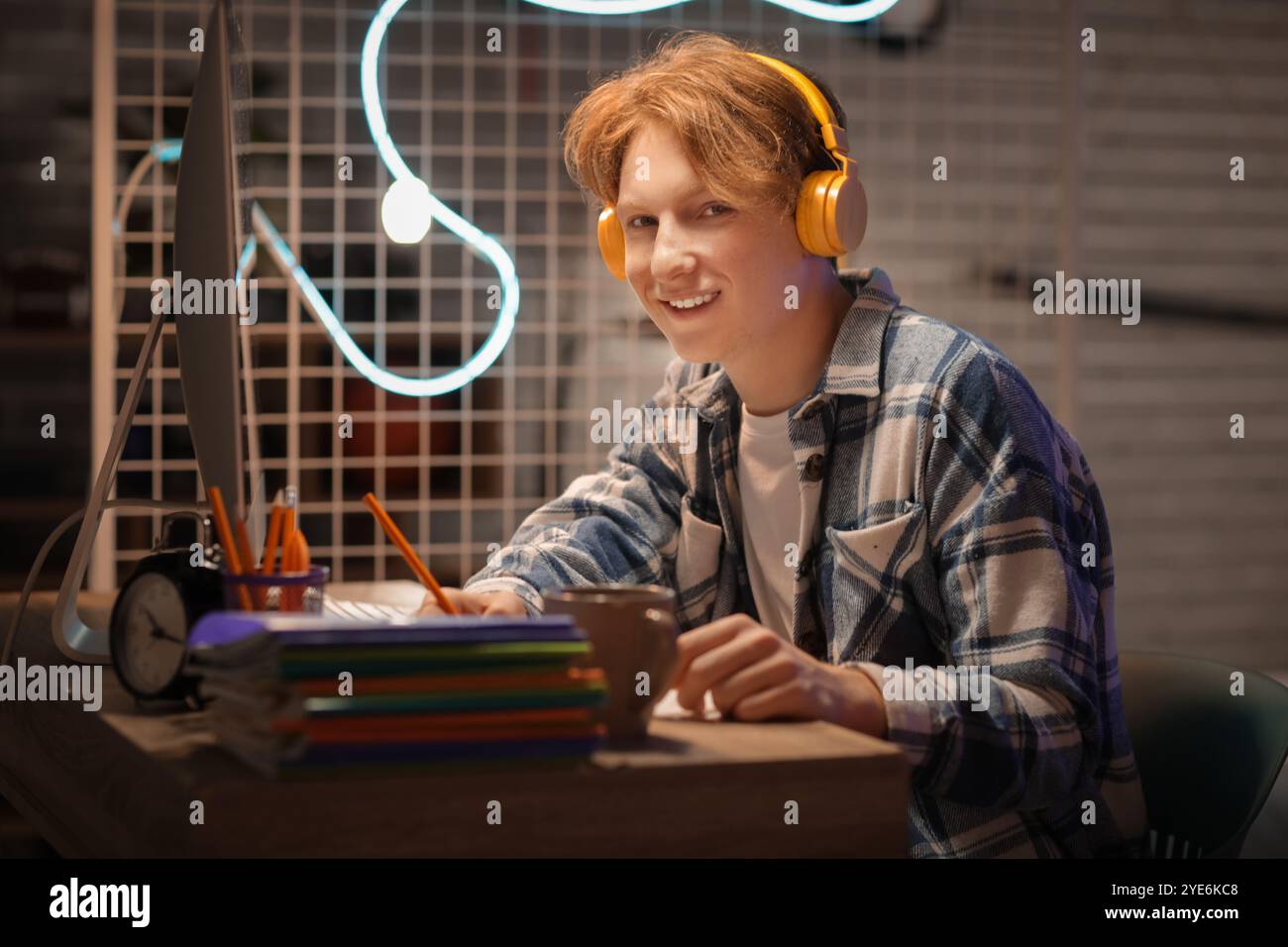 Male student with headphones studying in bedroom at night Stock Photo ...