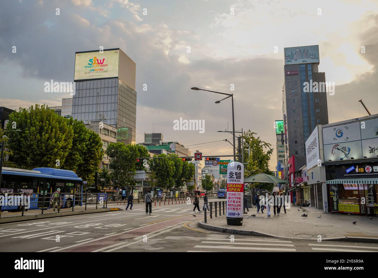Busy city street with a bus and a number of pedestrians. There are ...