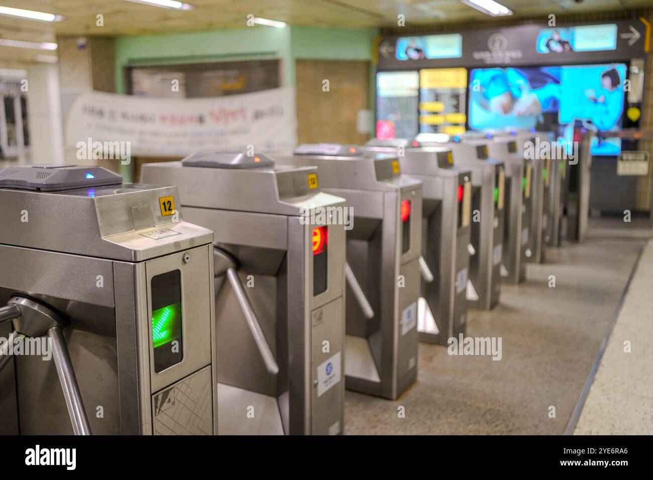Row of turnstiles with a green light on the left. There are also a few ...