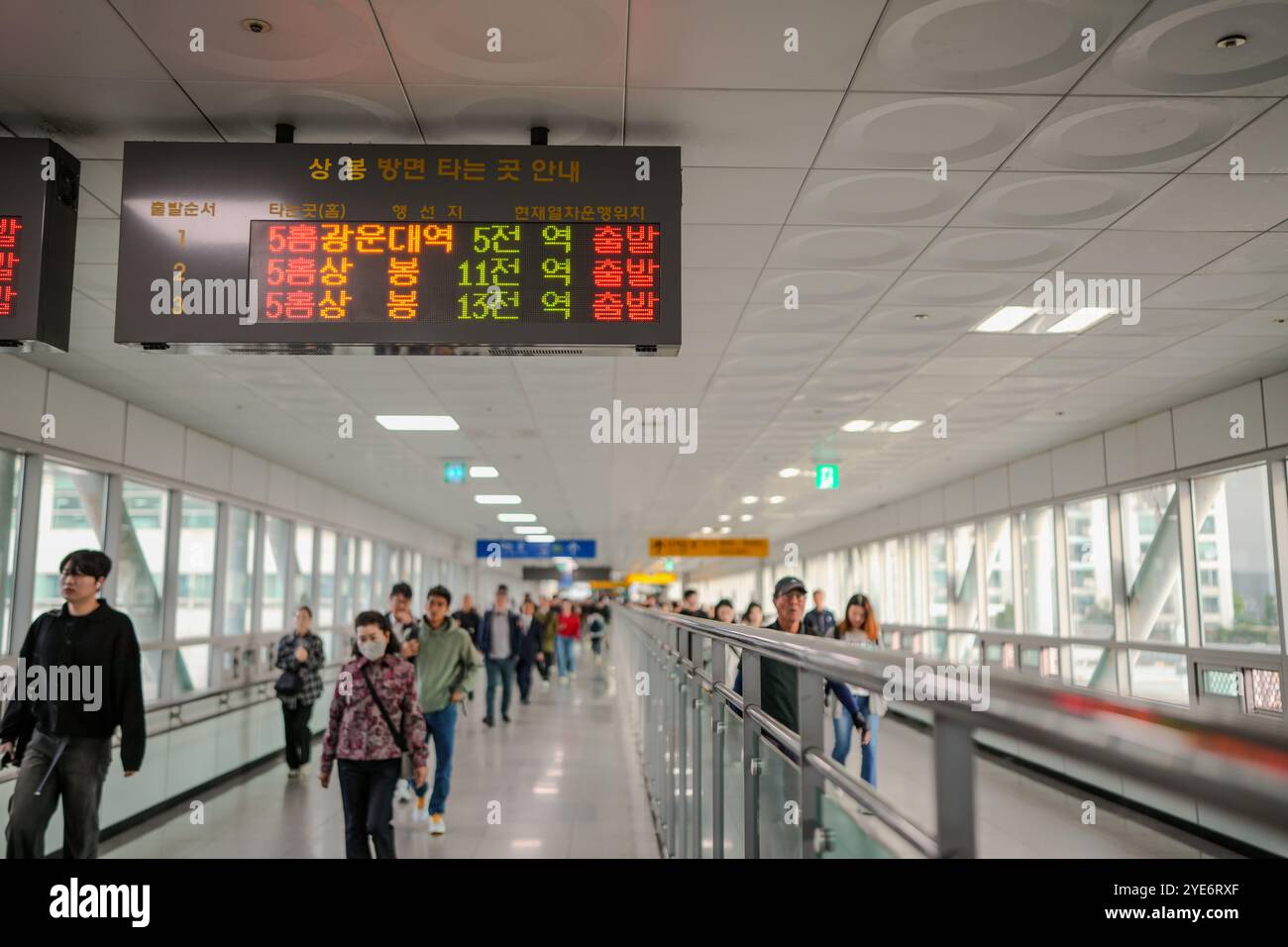 Group of people walking in a train station. The train station has a ...