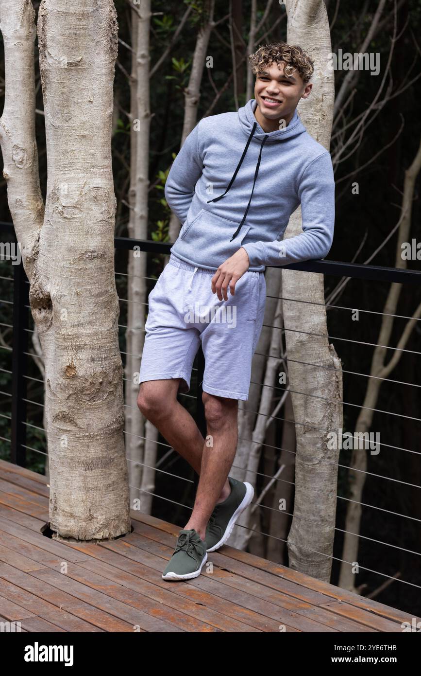 Smiling young man in casual wear leaning on railing on balcony Stock ...