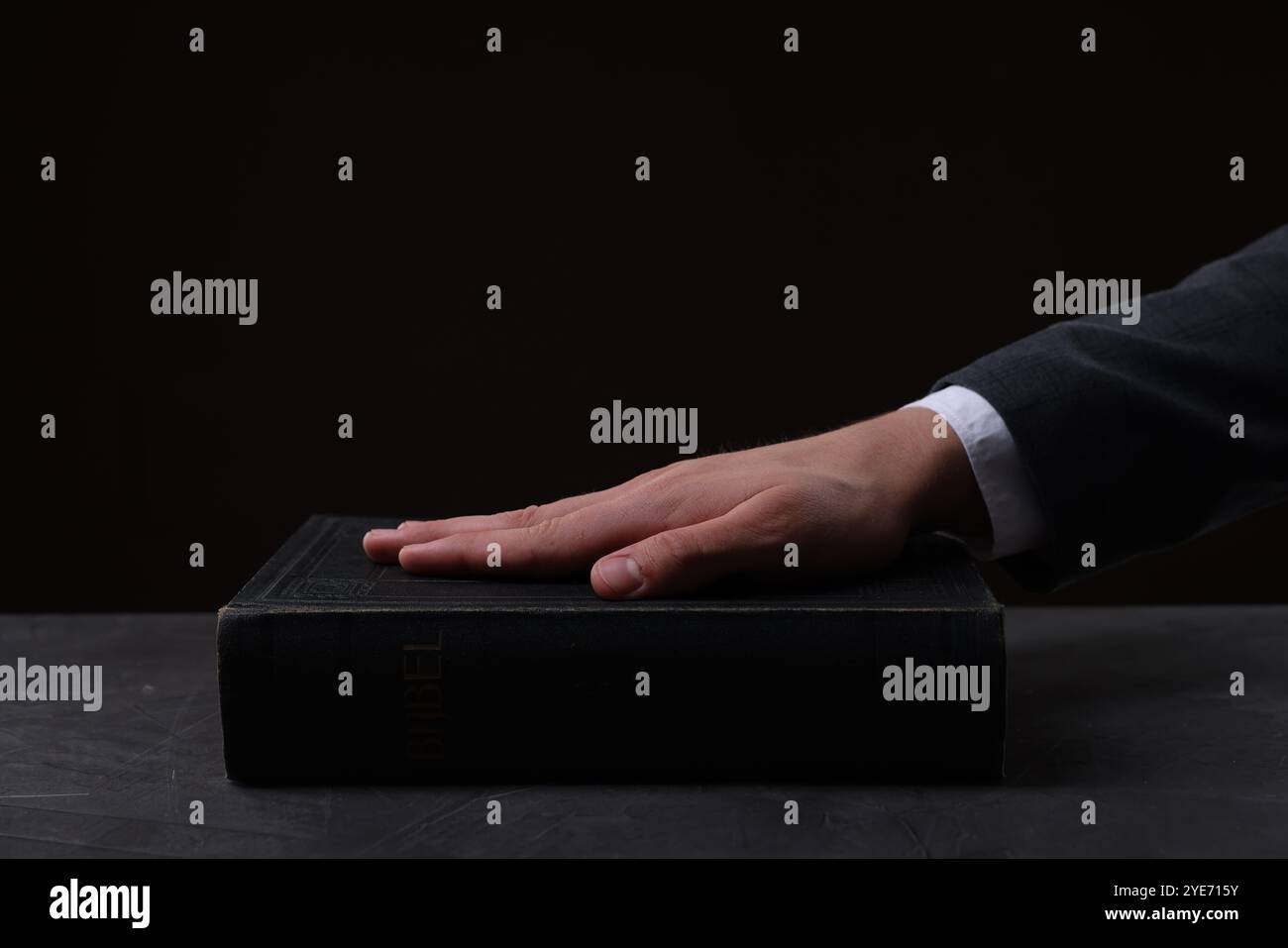 Man taking oath with his hand on Bible at black table, closeup Stock ...