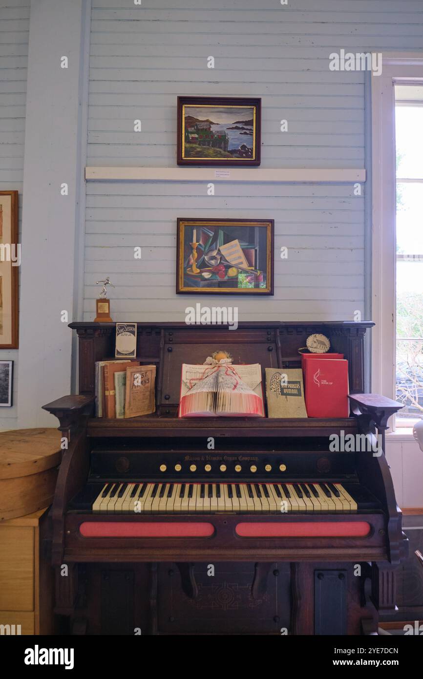 A display of an old, wood organ and some art on the wall. At the ...