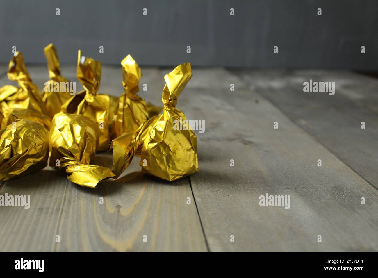 Chocolate candies in yellow golden wrappers on a gray background with ...