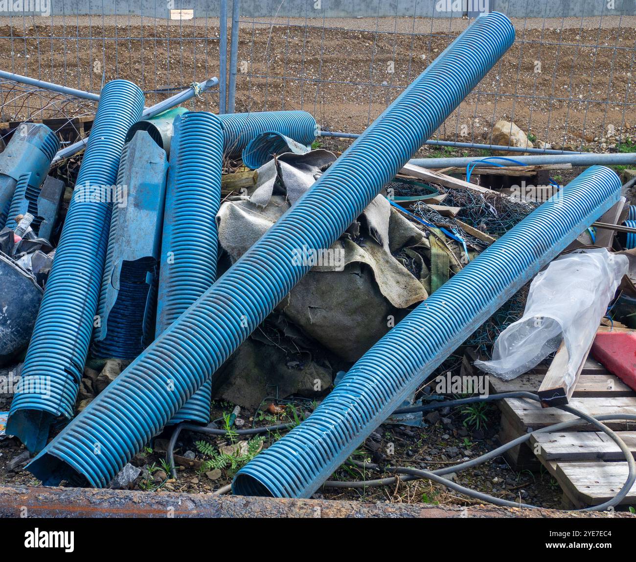 A pile of garbage with blue plastic pipes scattered throughout. The ...