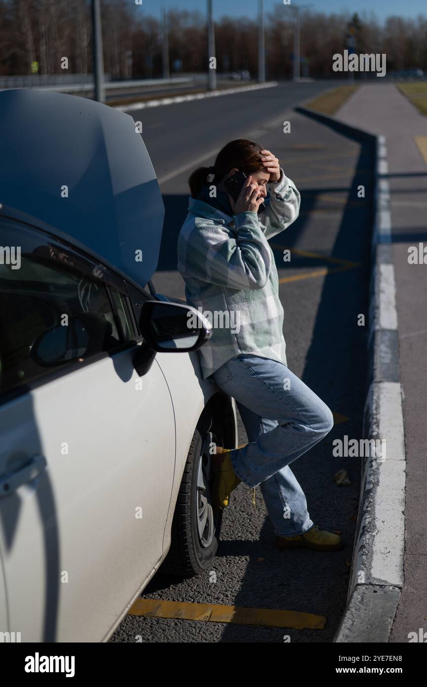 Sad Caucasian woman calling on phone while standing near car with open ...