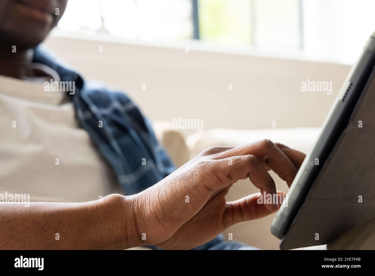 African american man relaxing at home using tablet, focusing on screen ...