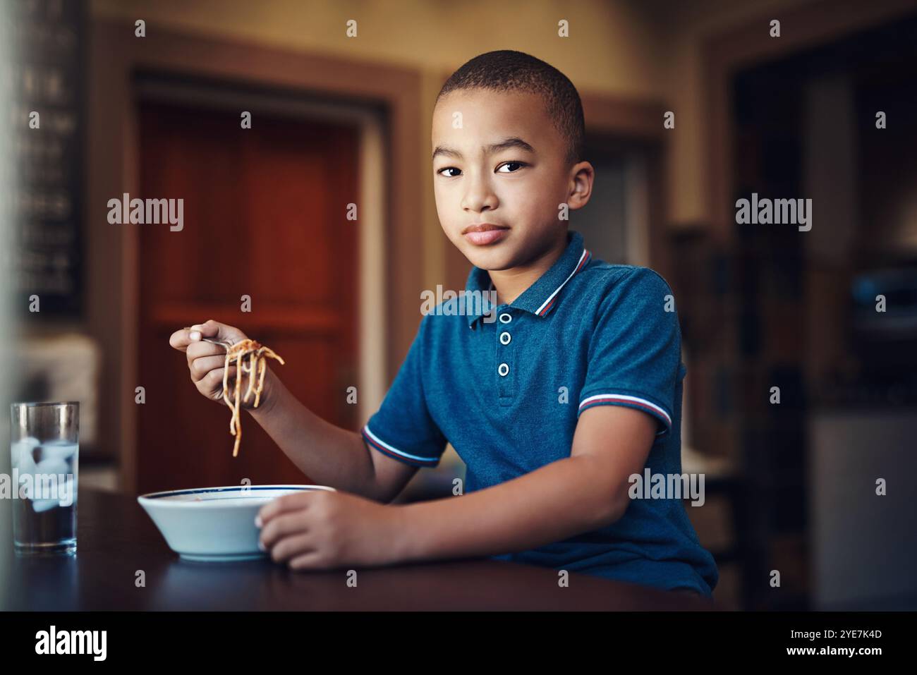 Child, portrait and eating pasta in home for nutrition, hungry or ...