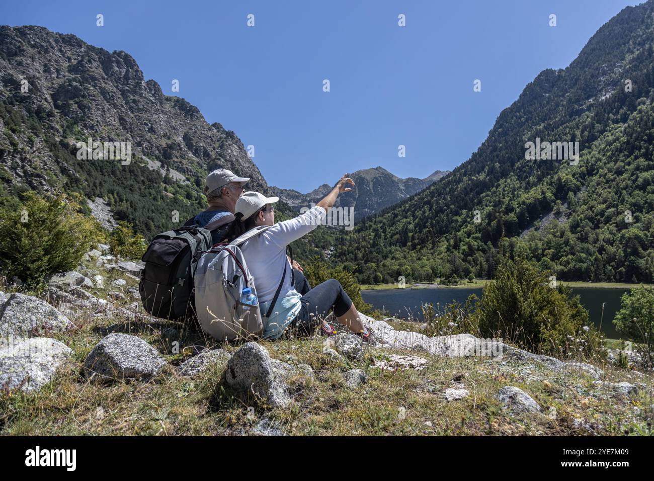 Side view of mid aged couple sitting on Spanish Pyrenees mountain and ...