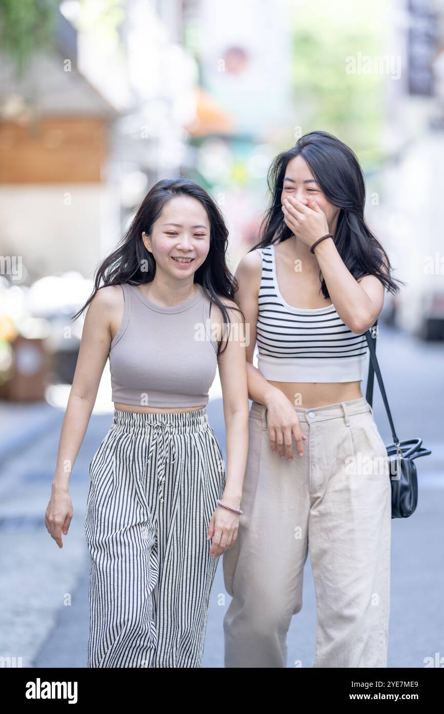 Two Taiwanese women in their 30s wearing casual outfits walk along ...