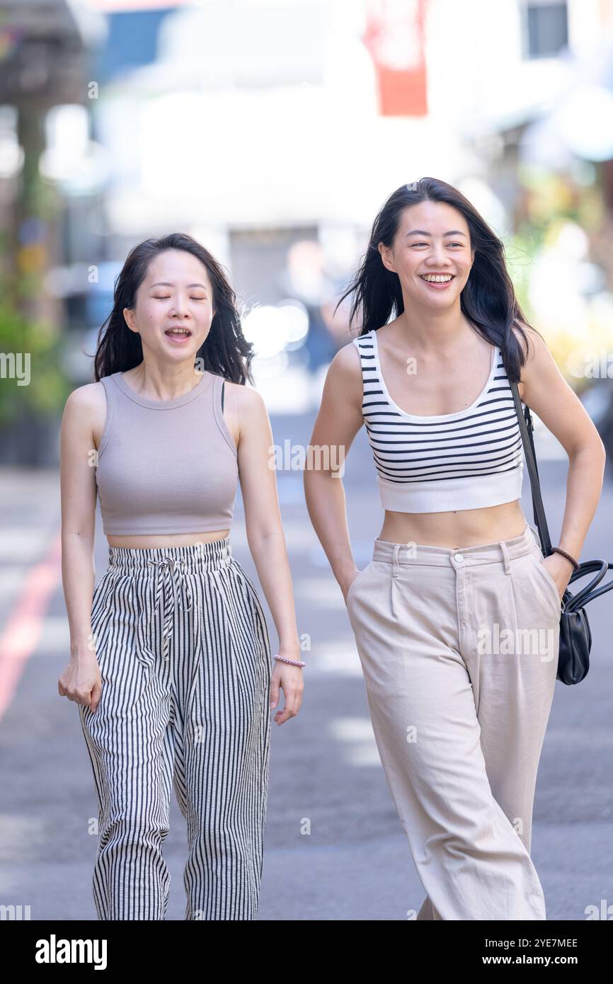 Two Taiwanese women in their 30s wearing casual outfits walk along ...