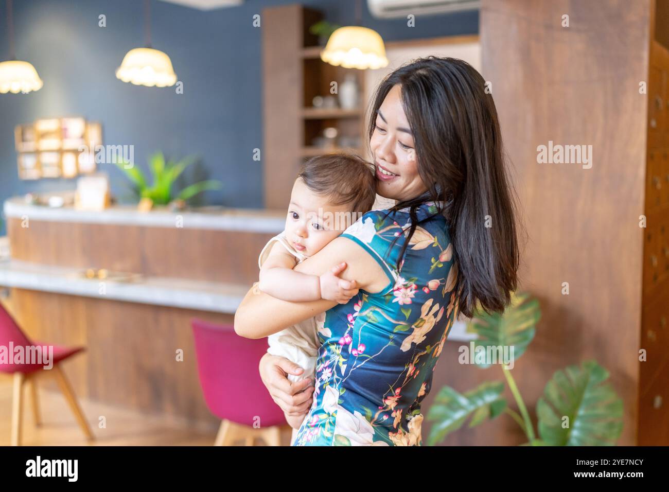 A 6-month-old baby held by a woman in her 30s wearing traditional ...