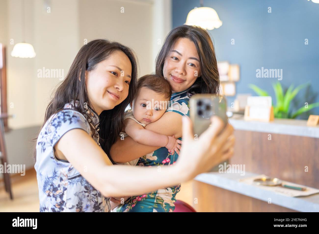 Two Taiwanese women in their 30s wearing traditional Chinese clothing hold a 6-month-old baby ...