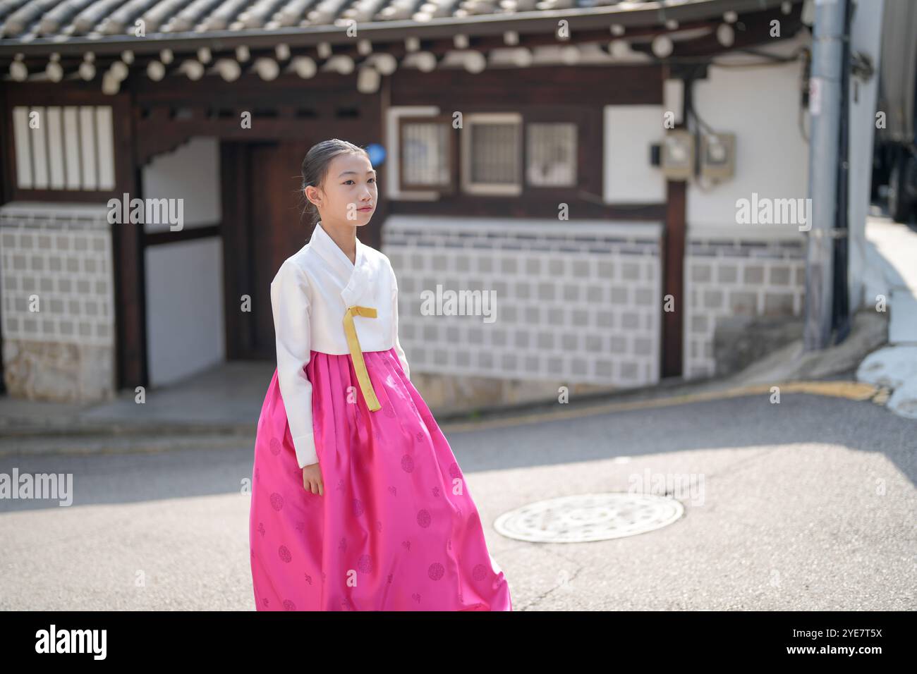A 9-year-old Korean girl wearing a hanbok is walking through the ...