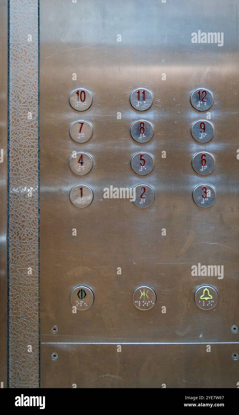 Round metallic buttons on a 12 storey elevator control panel with signs ...
