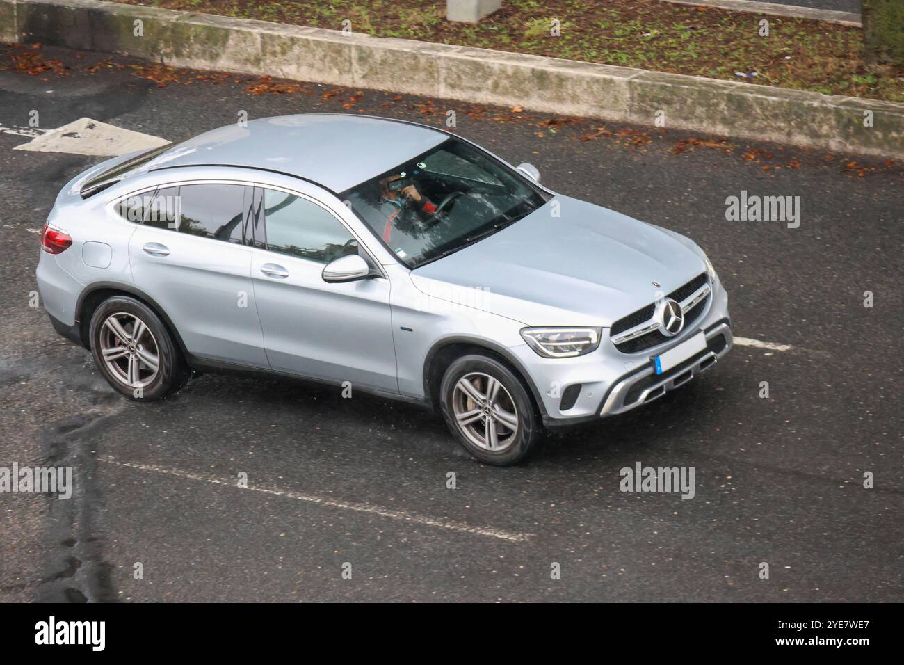 Modern silver metallic mercedes benz glc coupe is driving on a road ...