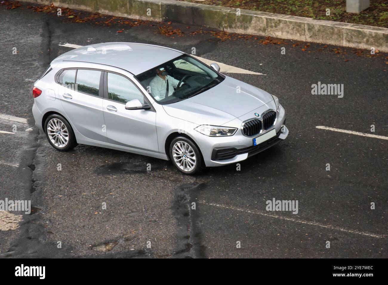 Modern silver compact hatchback car is being driven by a man in a white ...