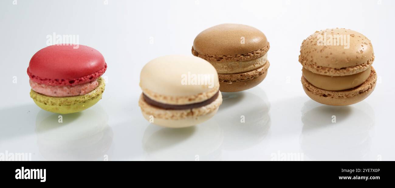 Four differently coloured macarons in front of a white background ...