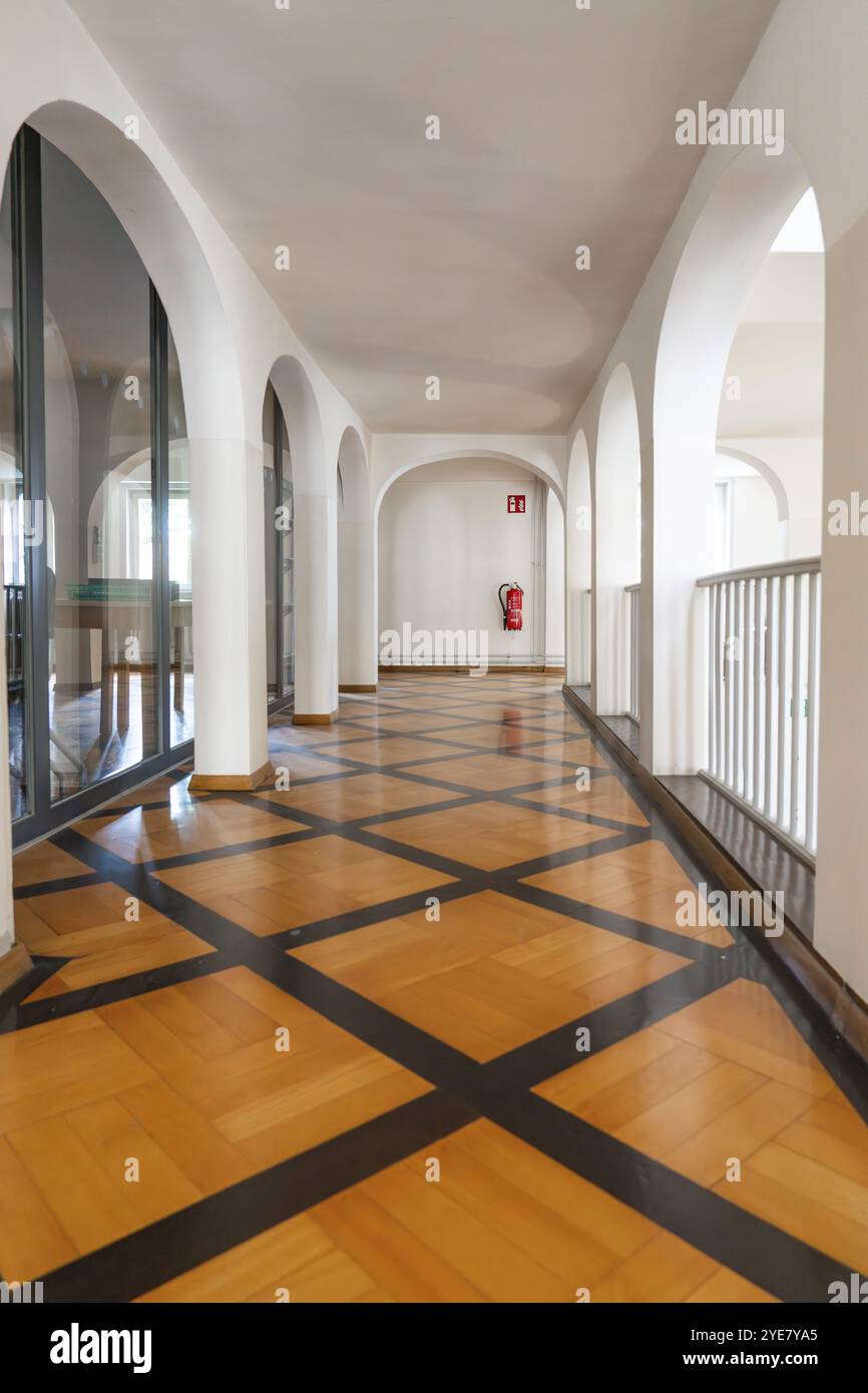 Modern hallway with arches and a striking wooden floor, bright ...