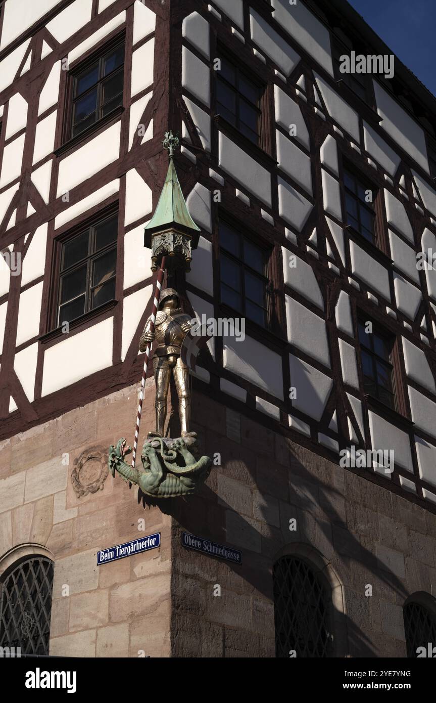 Statue of St George the Knight killing a dragon, half-timbered house ...