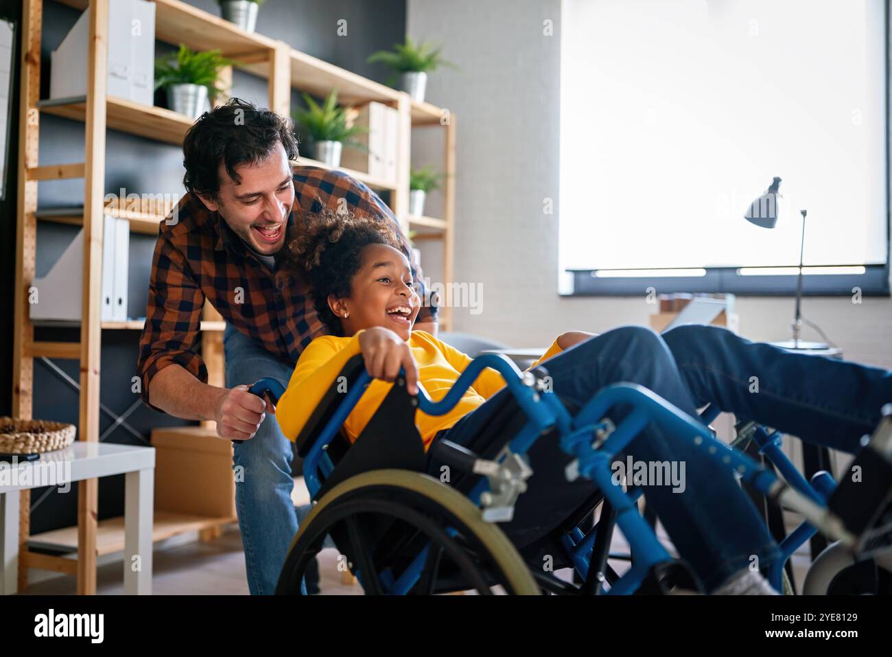 Child with disability in wheelchair at home having fun with father ...
