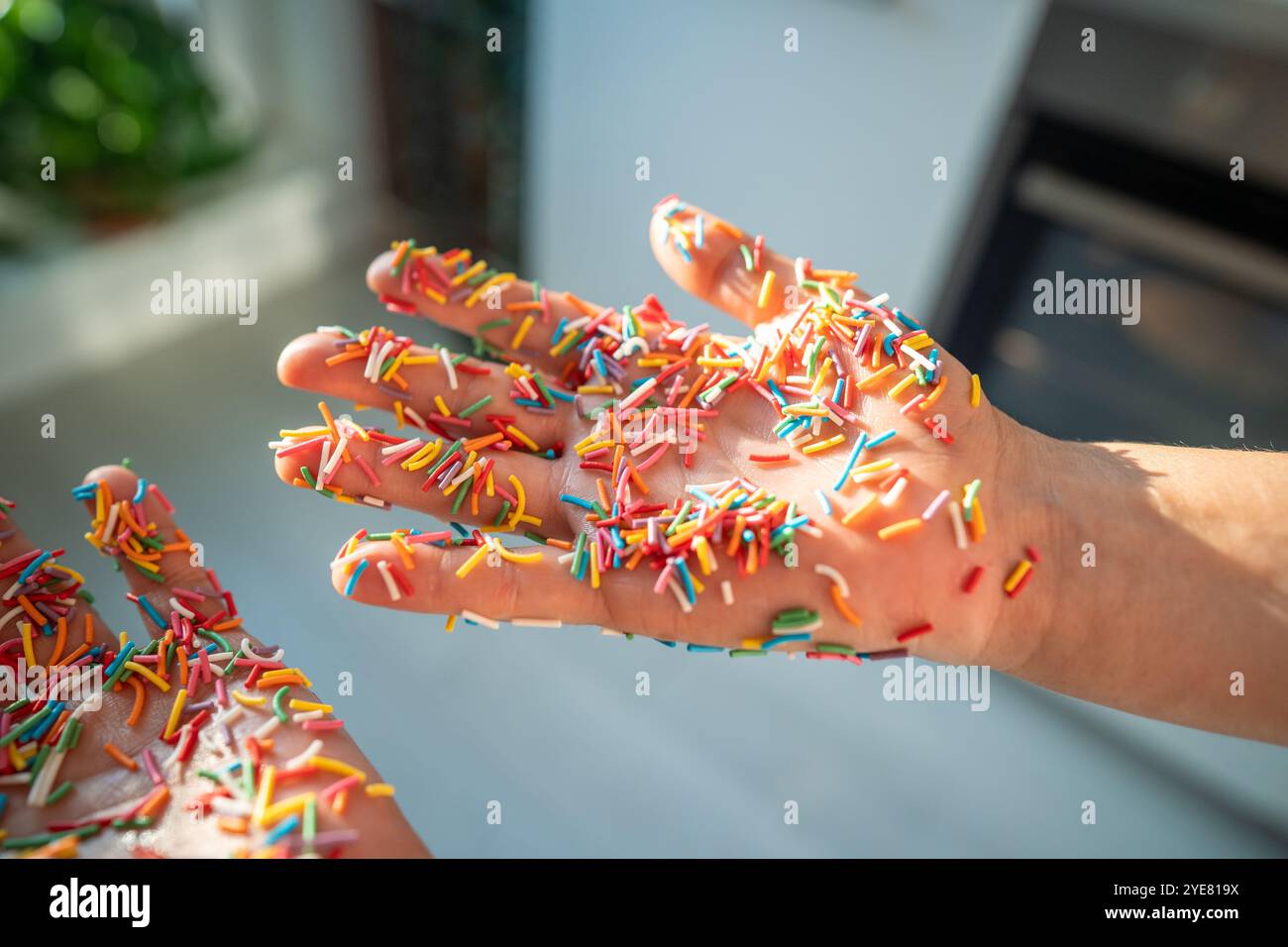 Hand covered in colorful baking sprinkles for donuts, cakes, sweet ...