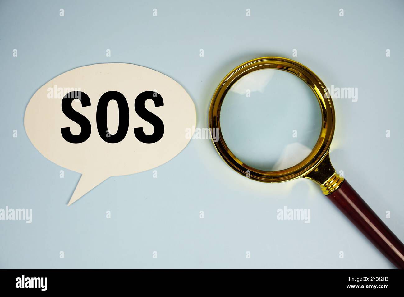 SOS text on speech bluble with magnifying glass top view on blue ...
