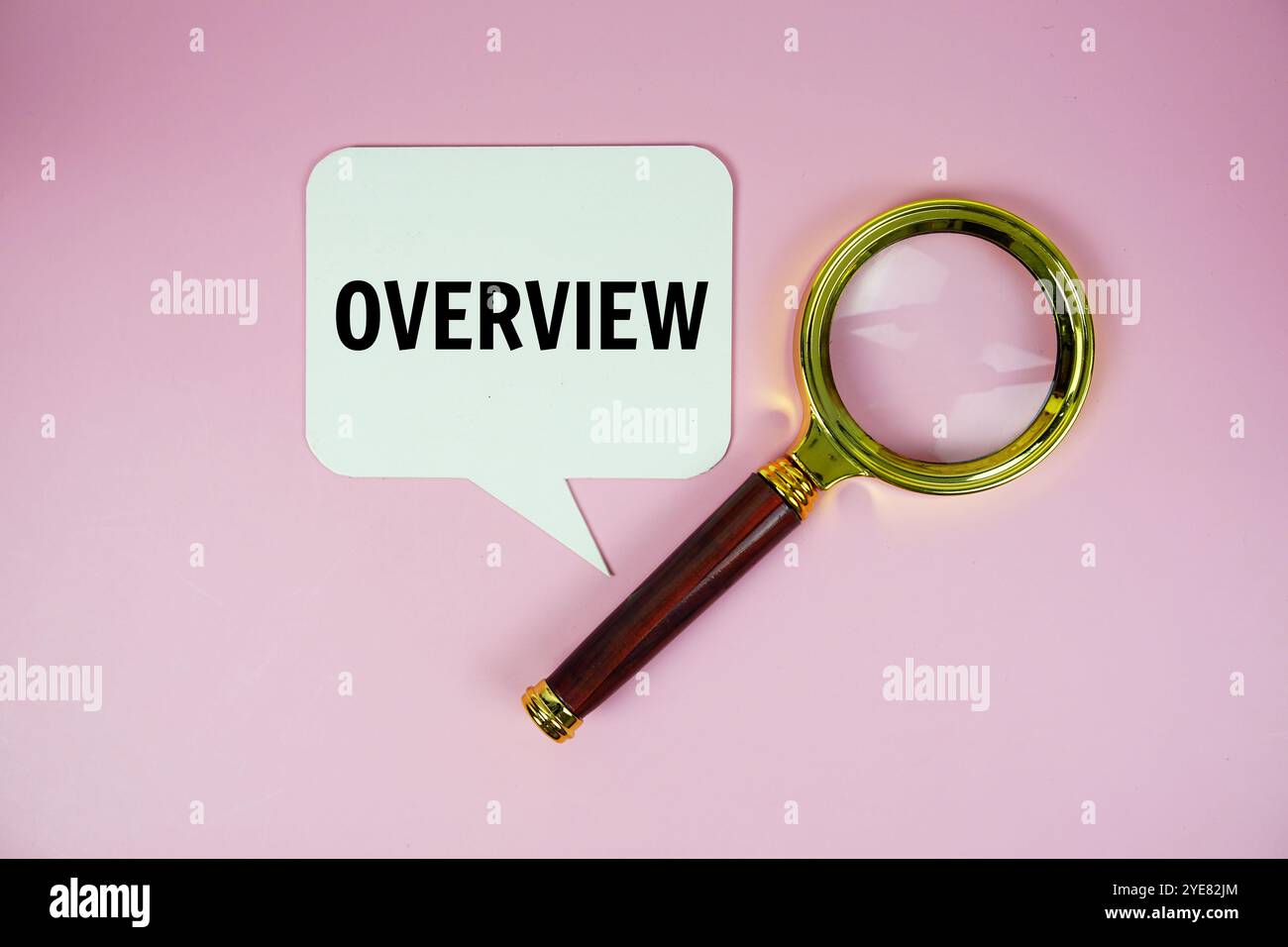 Overview text on speech bluble with magnifying glass top view on pink ...