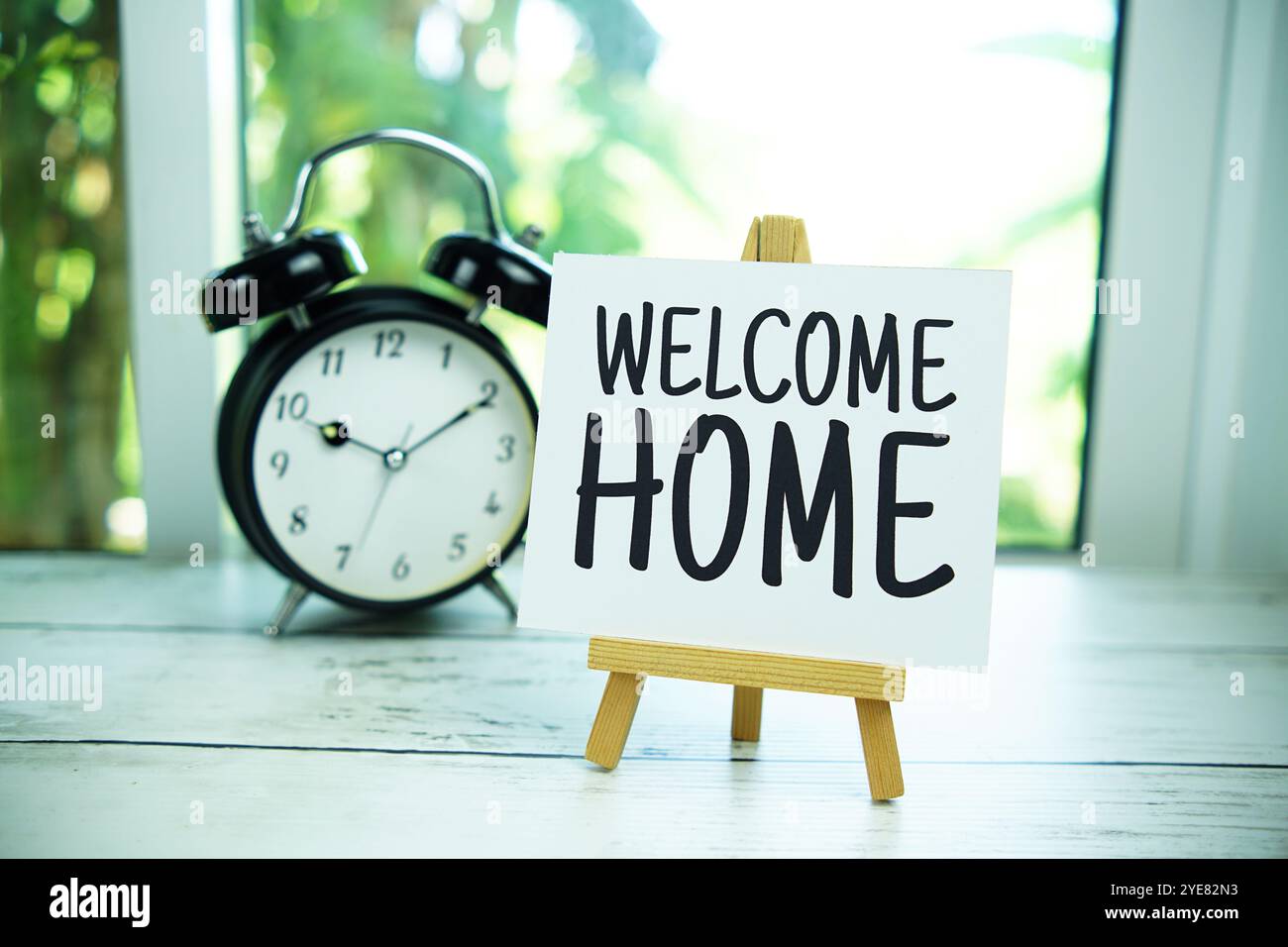 Welcome Home quotes text on paper card with easel and alarm clock in ...