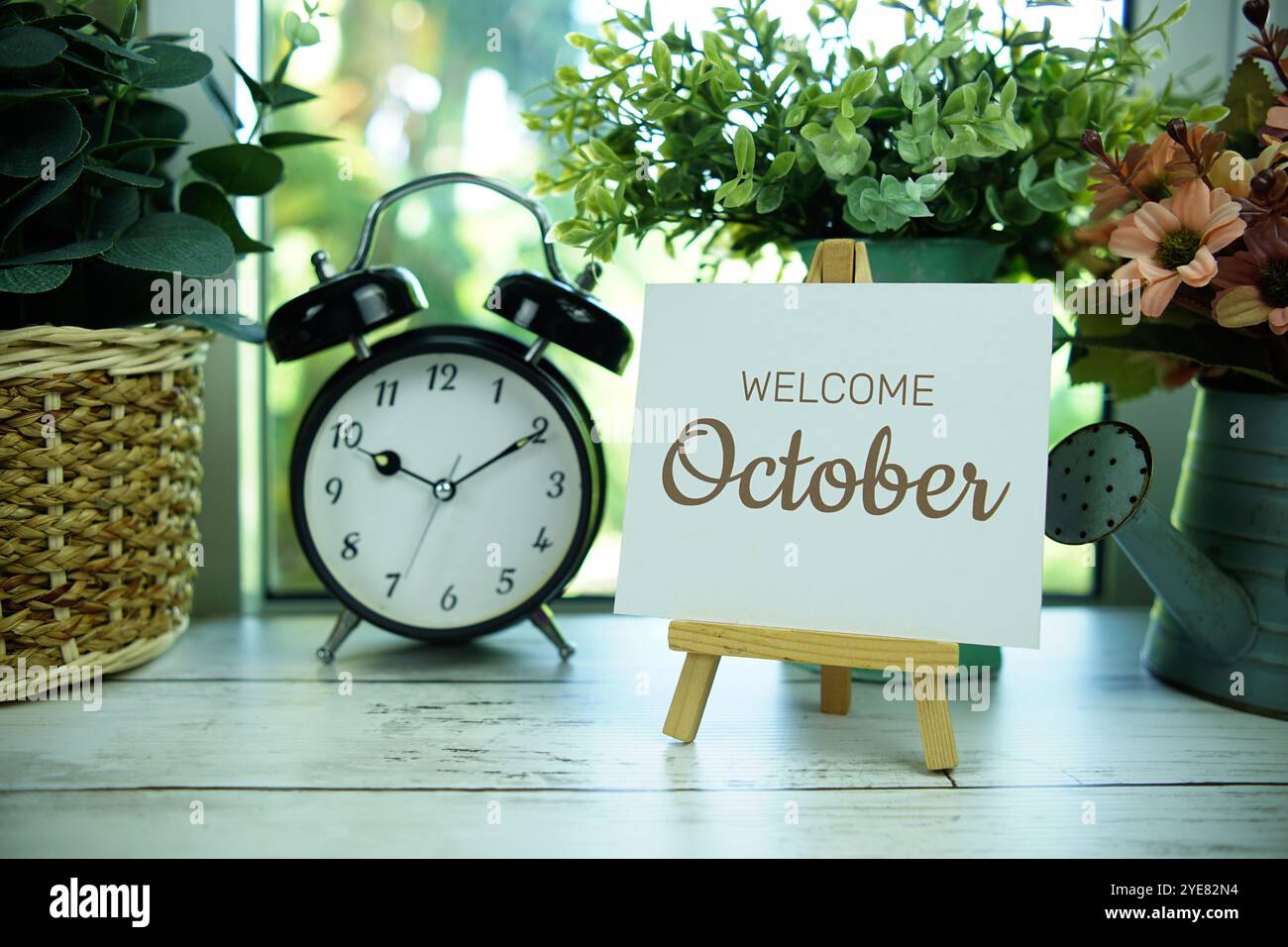 Welcome October text on paper card with easel and alarm clock in the ...