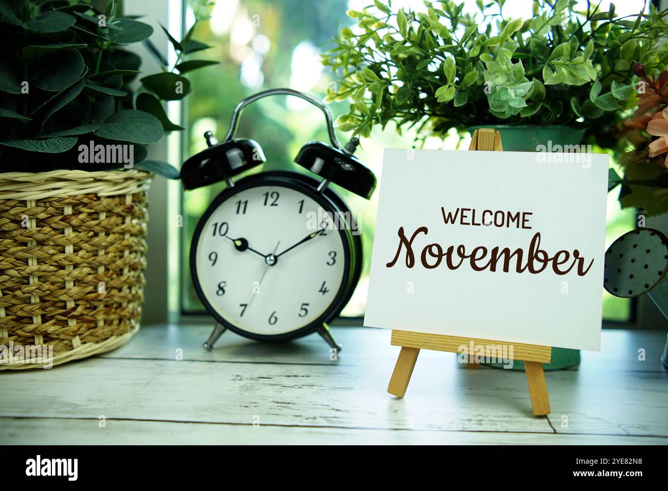 Welcome November text on paper card with easel and alarm clock in the ...