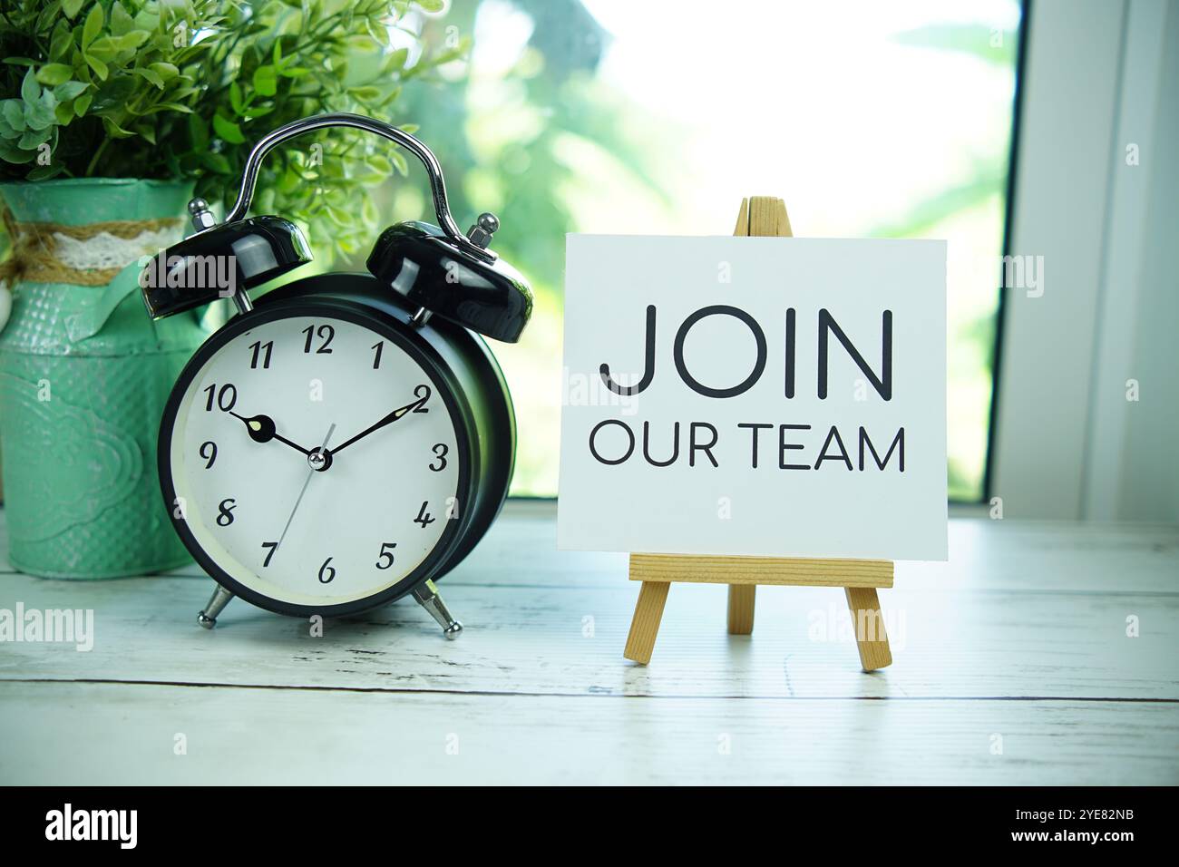 Join Our Team quotes text on paper card with easel and alarm clock in ...