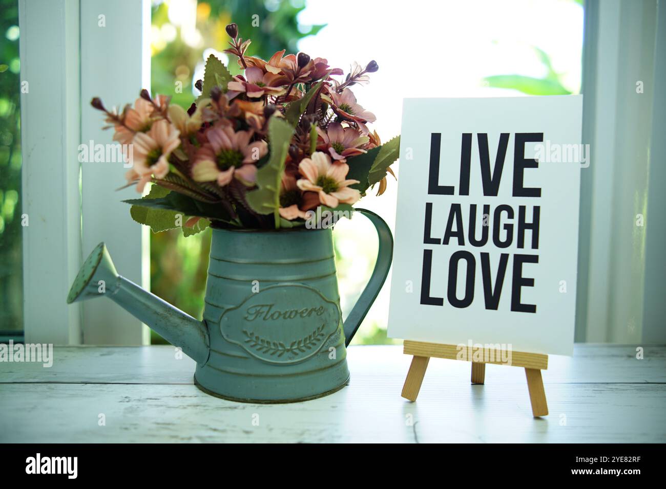 Live Laugh Love quotes text on paper card with easel and alarm clock in ...