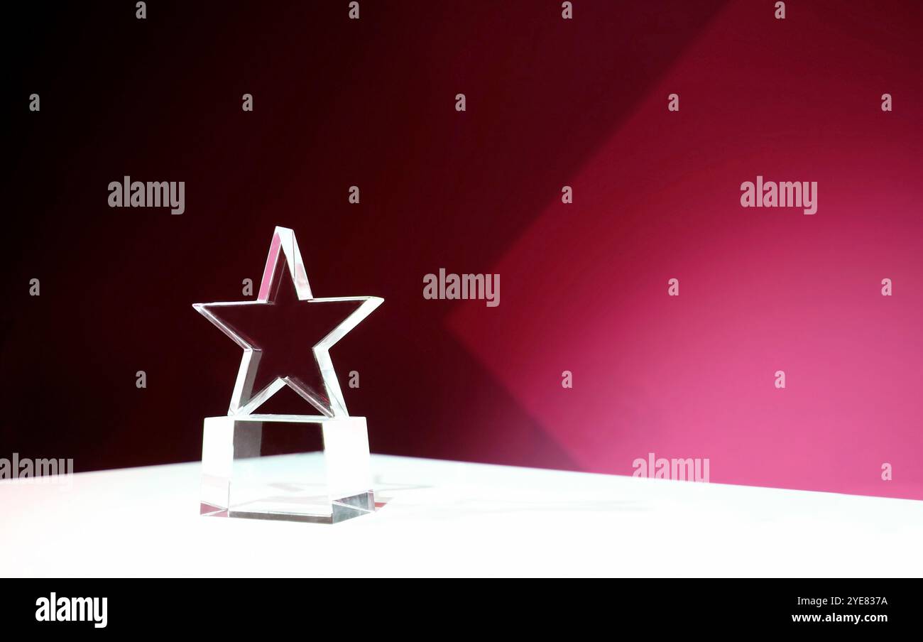 Star-shaped crystal prize on a table with pink spotlights and copy ...