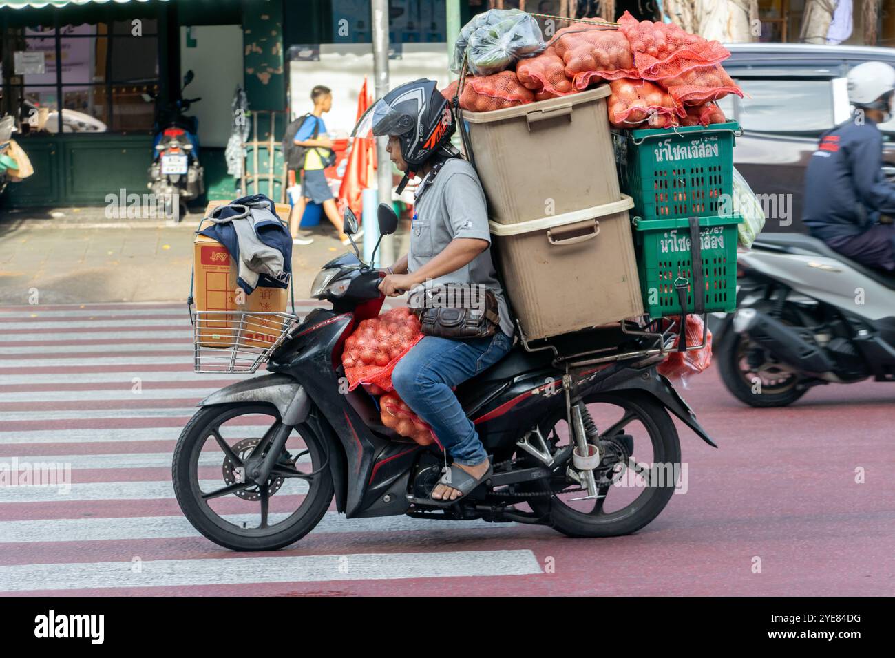 BANGKOK, THAILAND, JUNE 16 2024, A man rides a motorcycle fully loaded ...