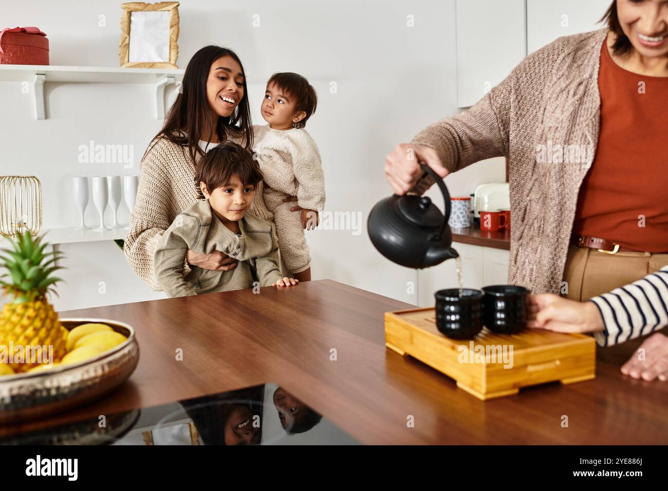 A happy family enjoys making tea together in a stylish kitchen ...