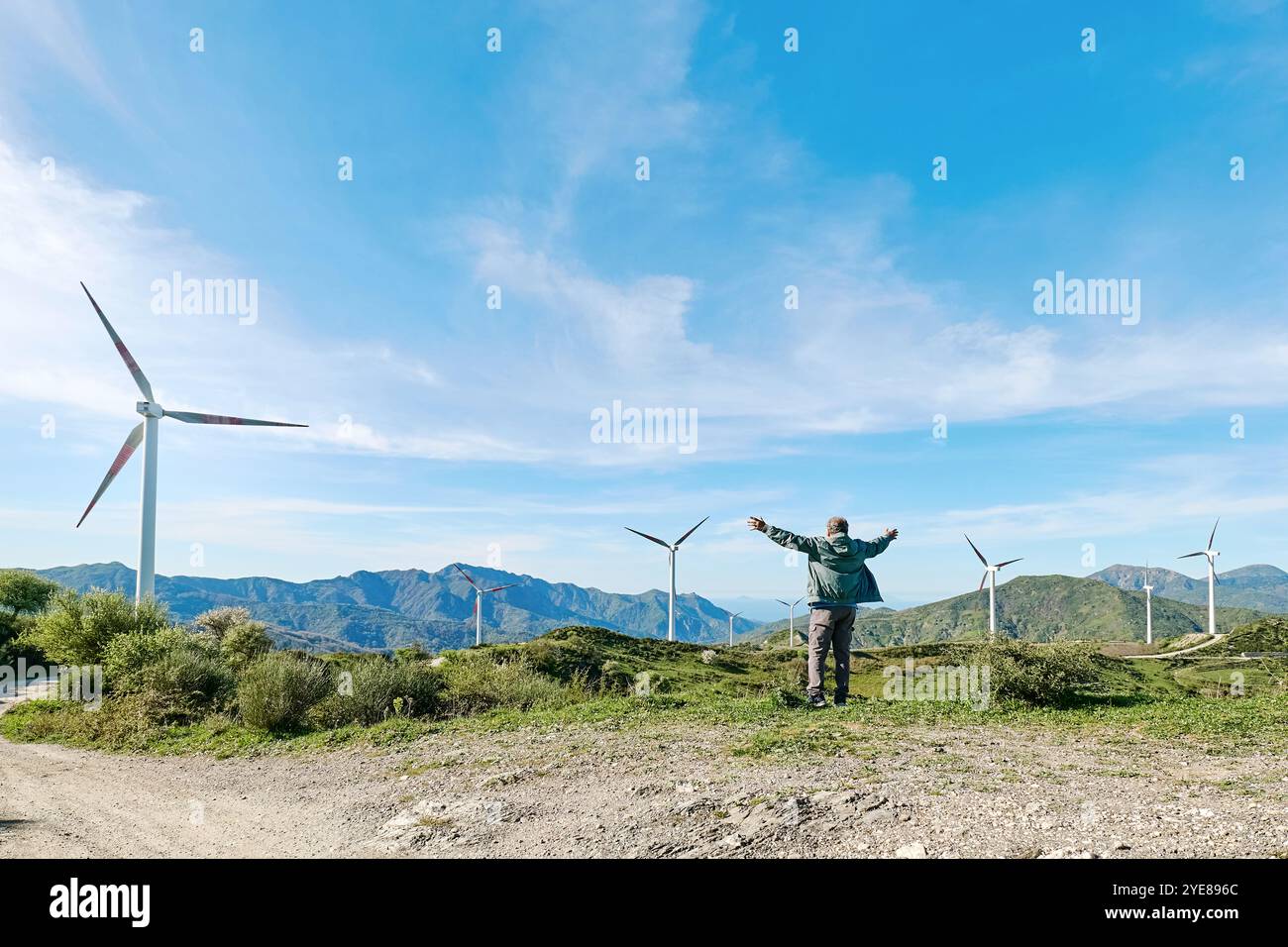 Rear view of man with open hands against of mountain top industrial ...