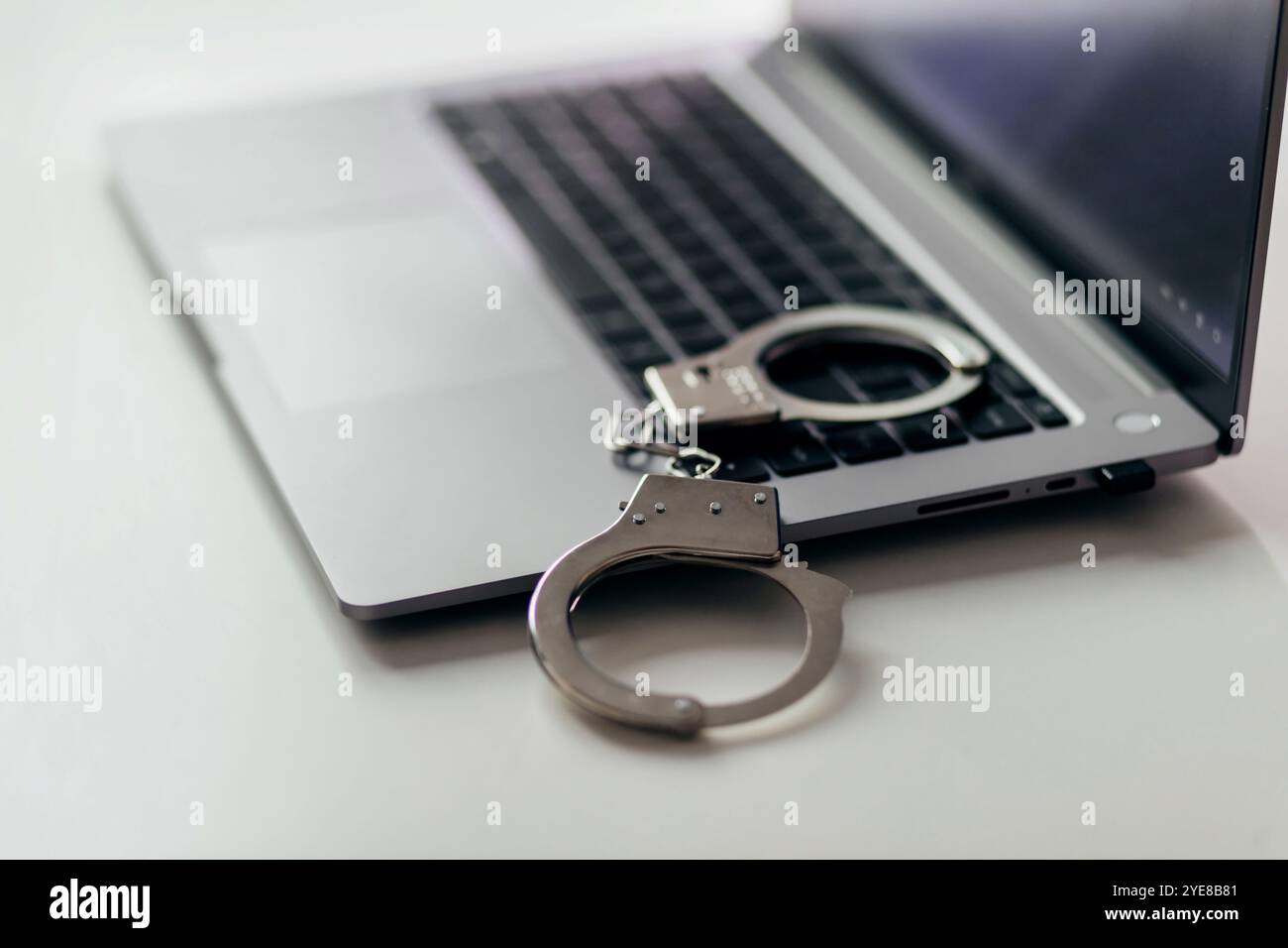 Handcuffs and laptop. Online piracy, fraud phishing, internet safety ...