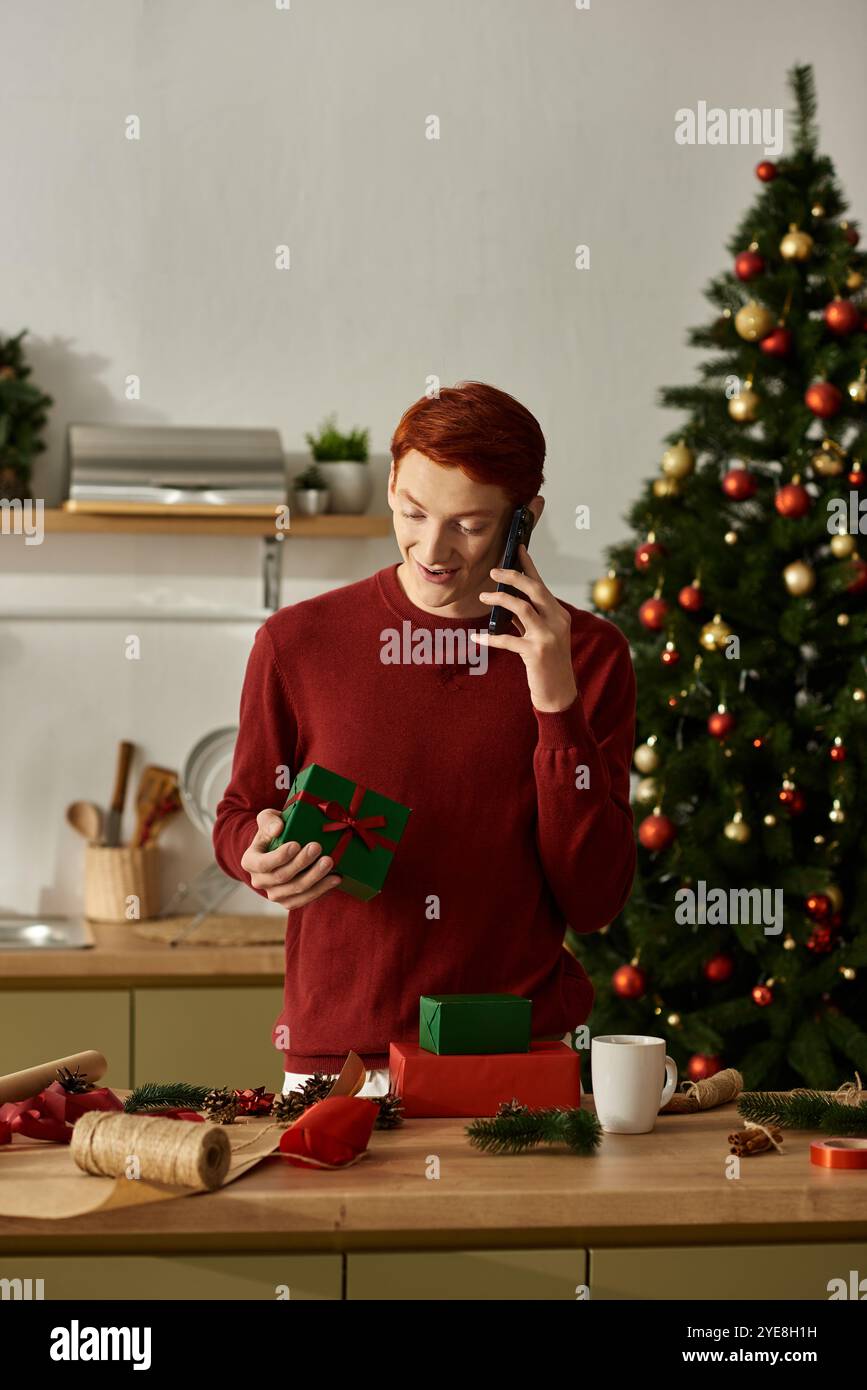 The young man smiles as he phones someone while wrapping Christmas ...
