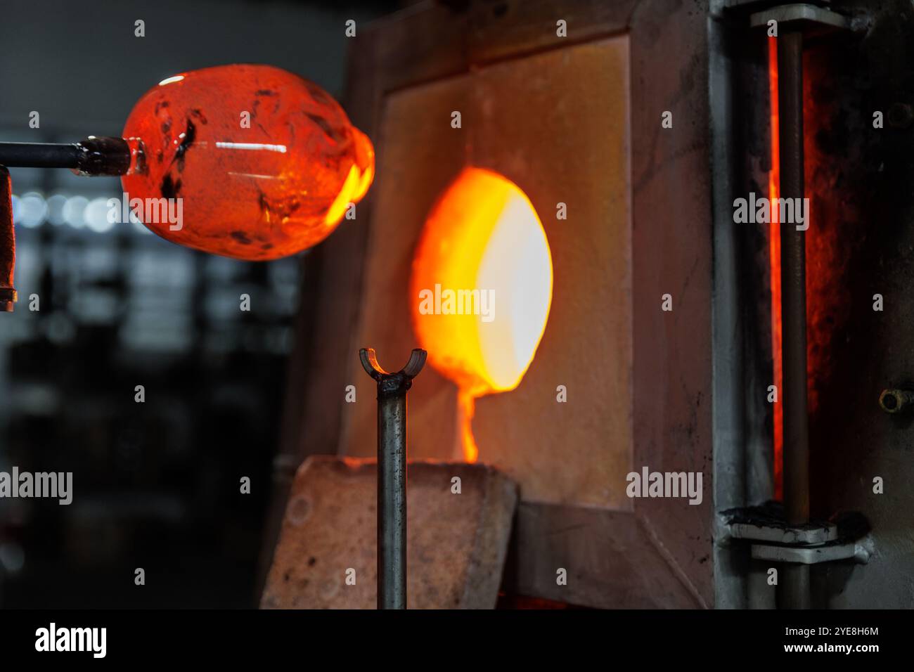 Close-up glassblowing process tube tool with molten glass shaped inside ...